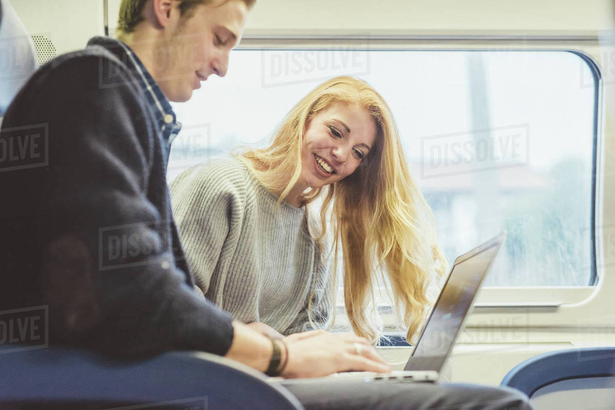 Young couple typing on laptop in train carriage, Italy - Stock Photo ...
