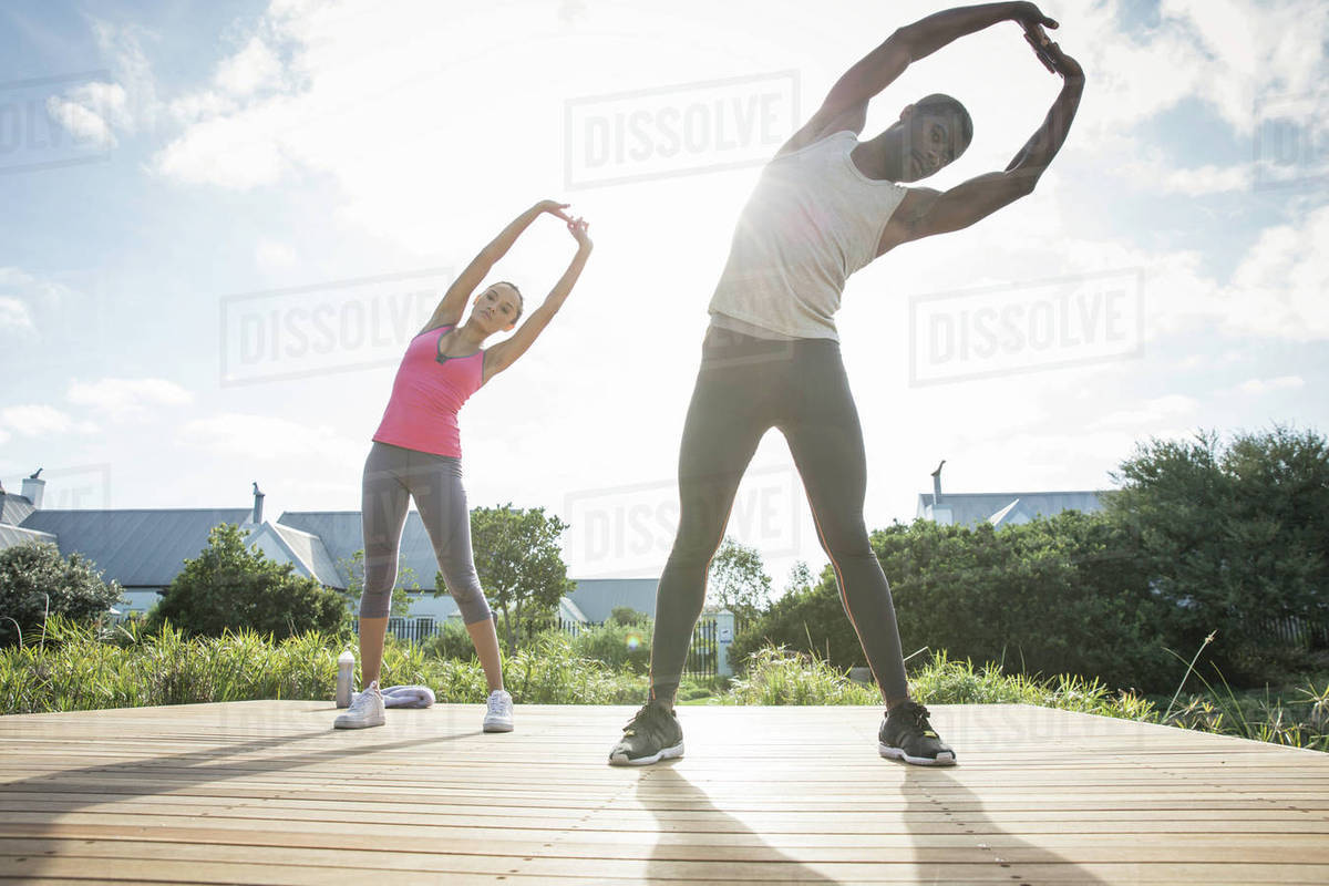 Couple, arms raised bending over sideways stretching - Stock Photo ...