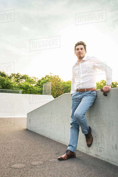 Smart young man leaning against wall - Stock Photo - Dissolve