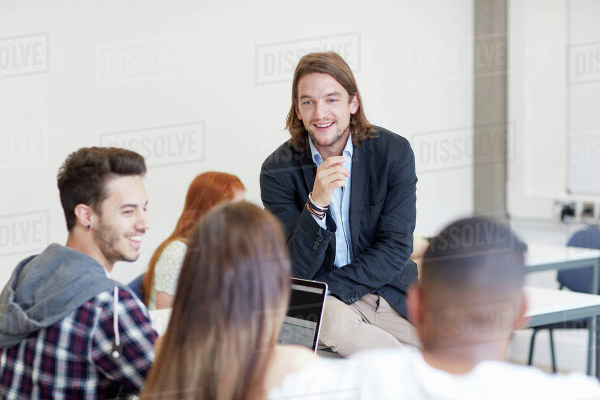 Male lecturer talking to students in higher education college classroom ...