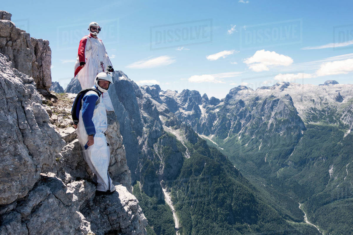 BASE jumpers getting ready to jump together from cliff, Italian Alps ...