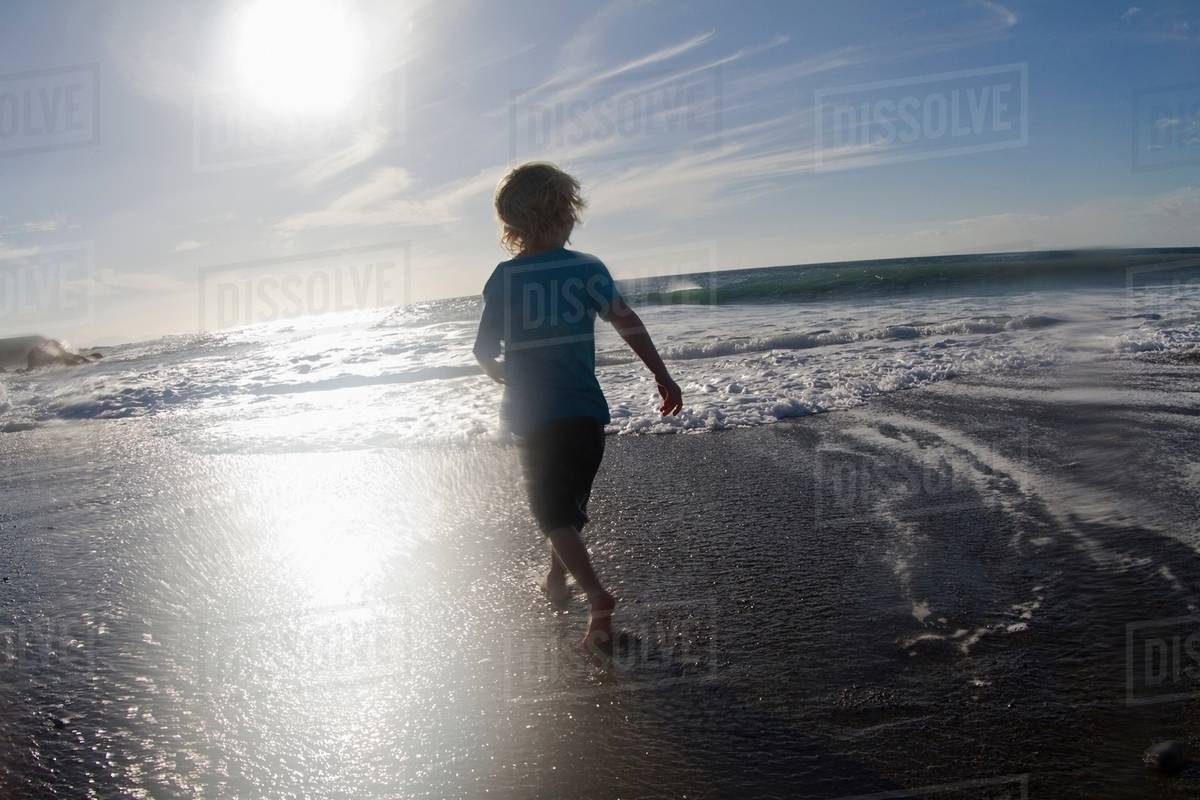 Boy playing in waves on beach - Royalty-free Stock Photo | Dissolve