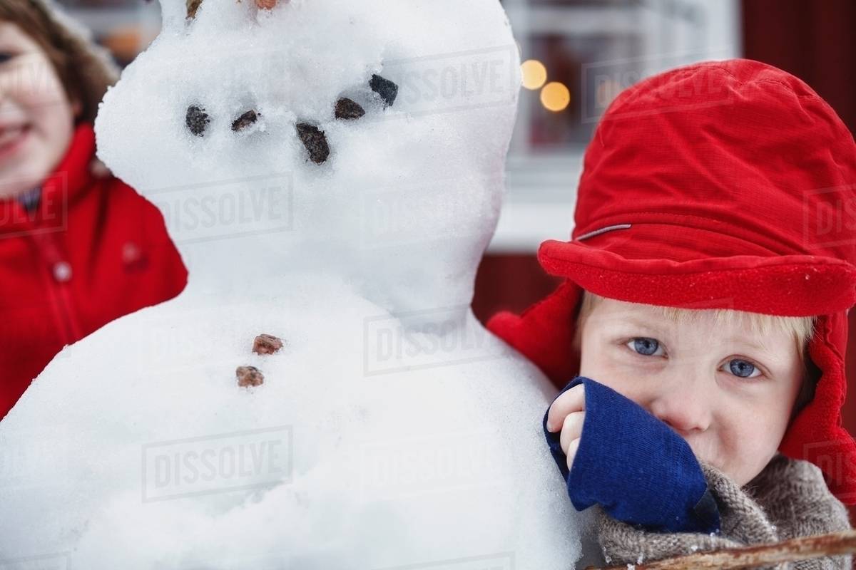 Close up of boy hugging snowman - Royalty-free Stock Photo | Dissolve