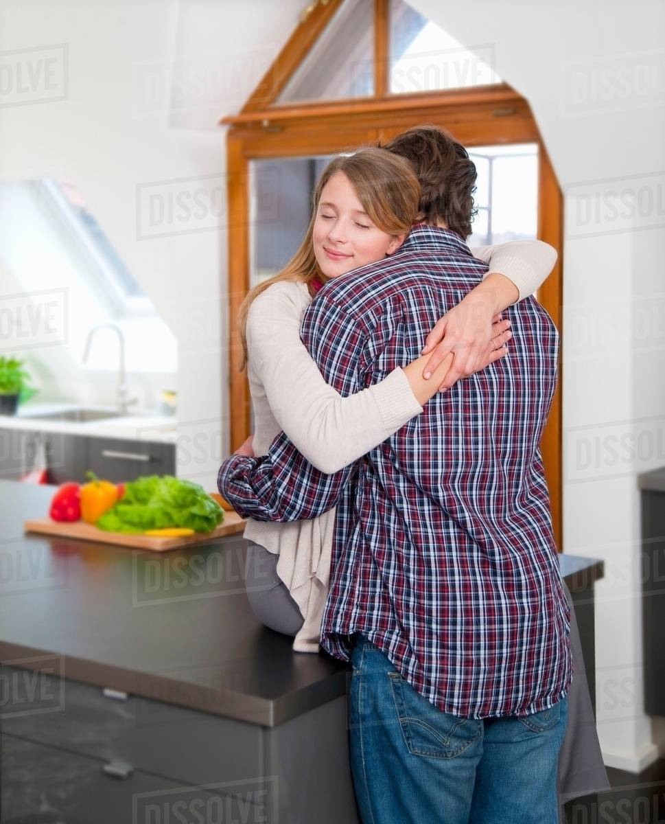 Couple hugging in kitchen - Stock Photo - Dissolve