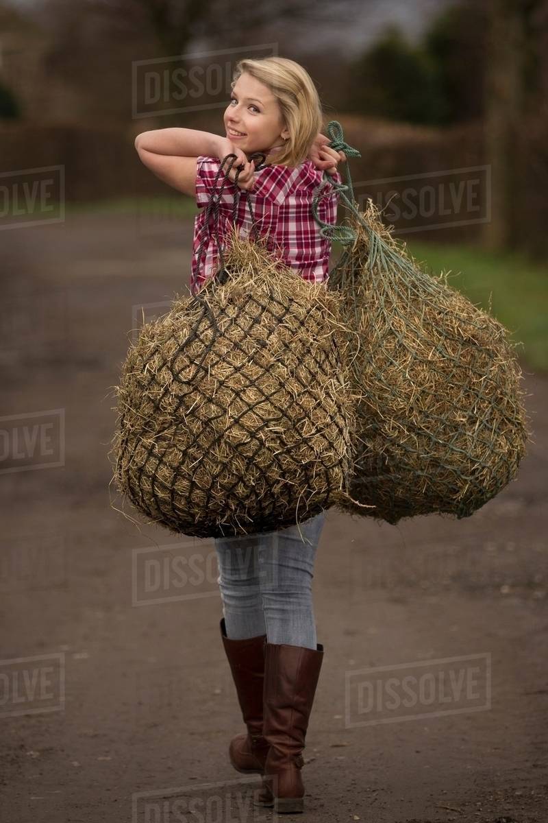 Teenage girl carrying hay on dirt path - Royalty-free Stock Photo ...