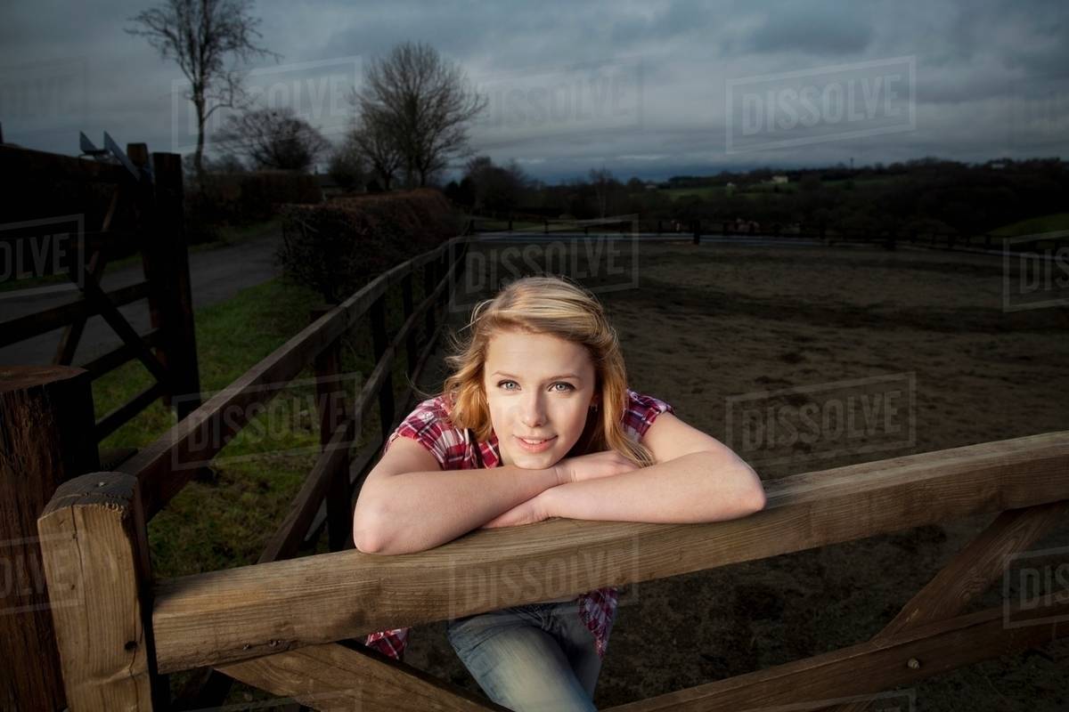 Teenage girl leaning on wooden fence - Royalty-free Stock Photo | Dissolve
