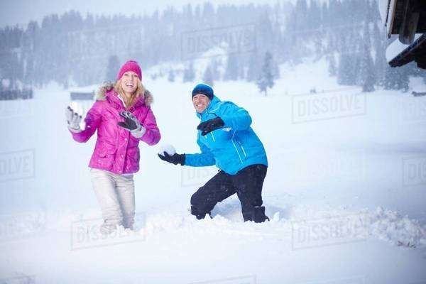 Couple having snowball fight outdoors - Royalty-free Stock Photo | Dissolve
