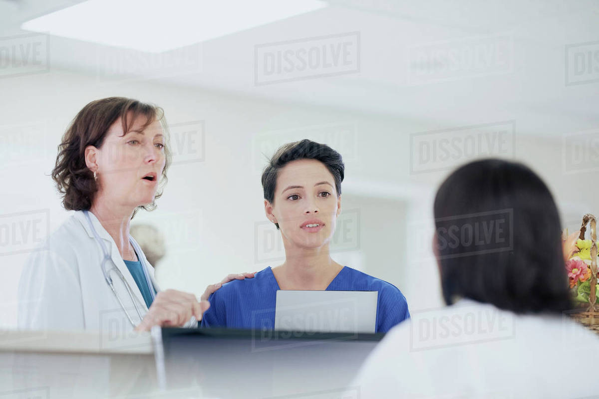 Female doctor having discussion with nurses at nurses station in ...