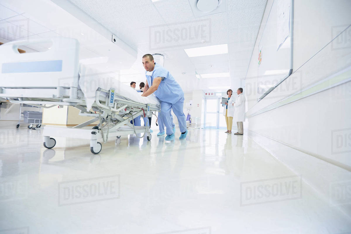 Medics urgently pushing hospital bed along corridor - Royalty-free ...