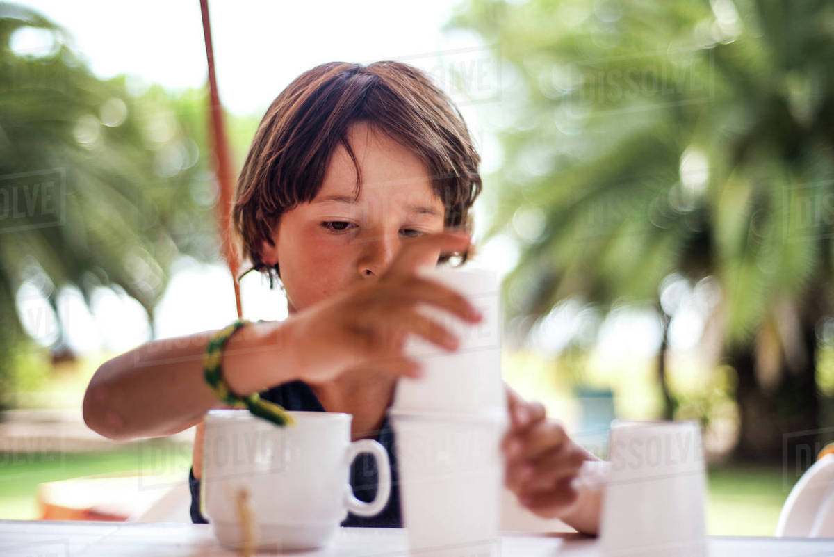 Boy balancing plastic cups - Stock Photo - Dissolve