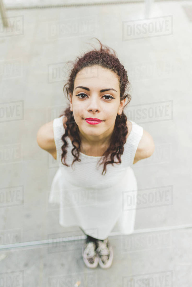 High angle portrait of woman, hands behind back looking at camera ...