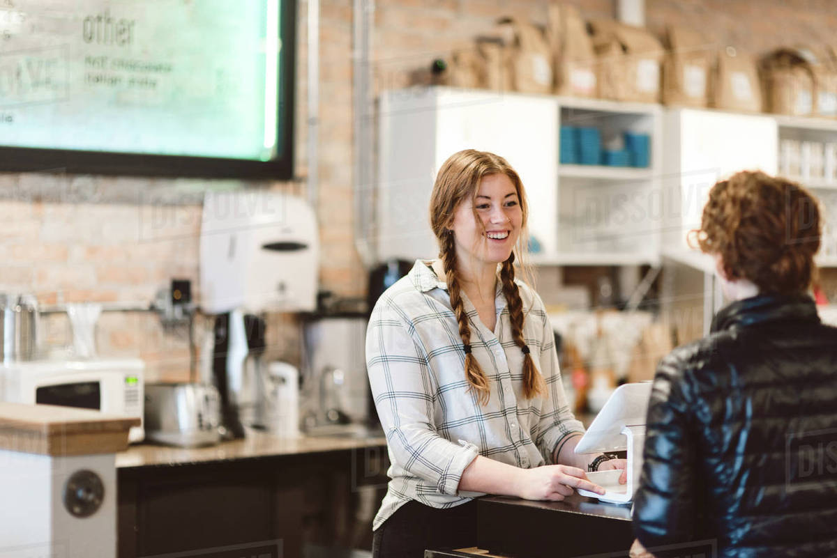 Cashier attending to customer in cafe - Stock Photo - Dissolve