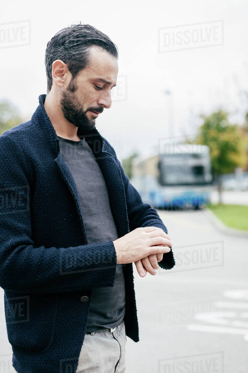 Man looking at wristwatch - Stock Photo - Dissolve