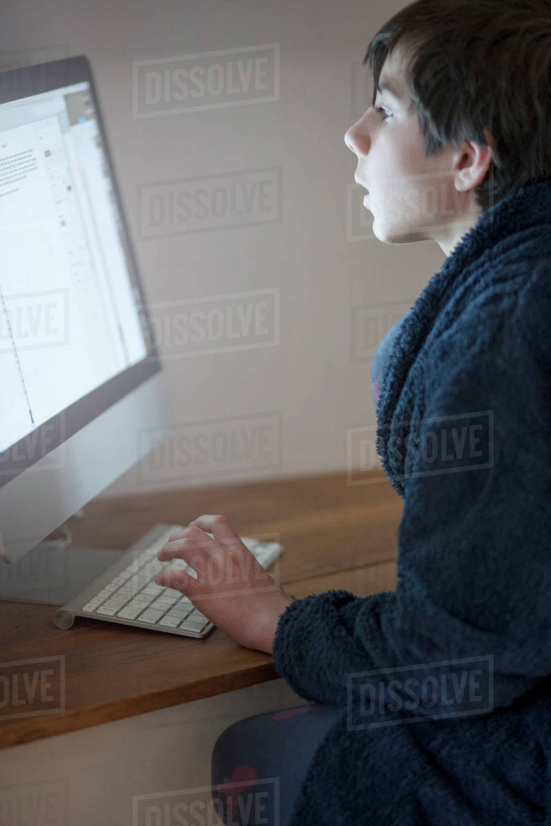 Boy in dressing gown typing on computer at home - Royalty-free Stock ...
