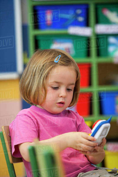 Preschool girl pressing toy cellphone buttons in classroom - Royalty ...