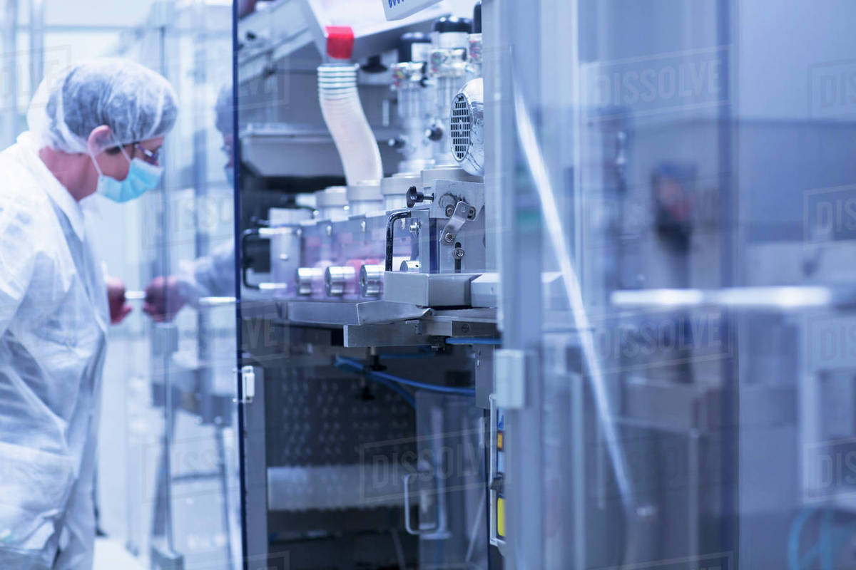 Worker operating machinery in pharmaceutical plant - Stock Photo - Dissolve