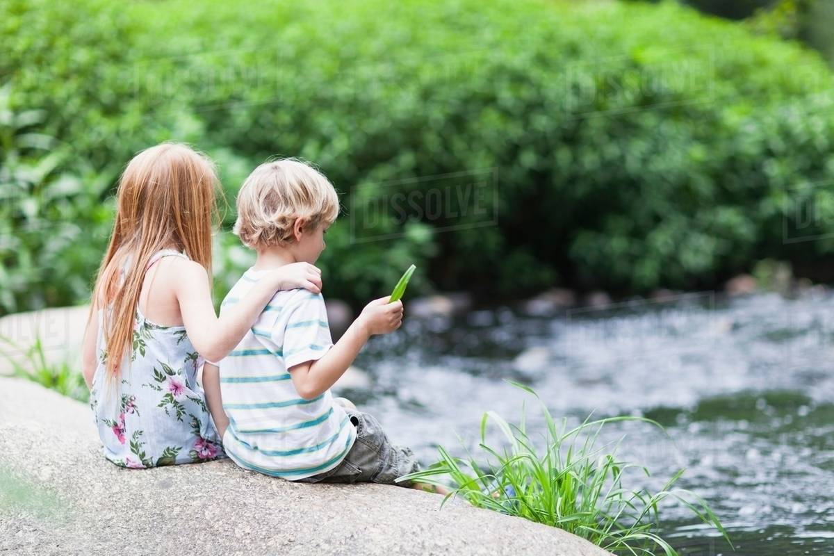 Children sitting on rock together - Royalty-free Stock Photo | Dissolve