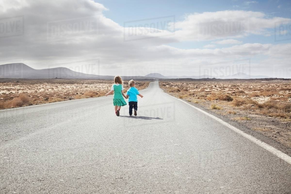 Children walking on paved rural road - Stock Photo - Dissolve
