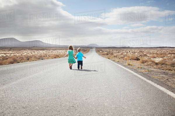 Children walking on paved rural road - Stock Photo - Dissolve