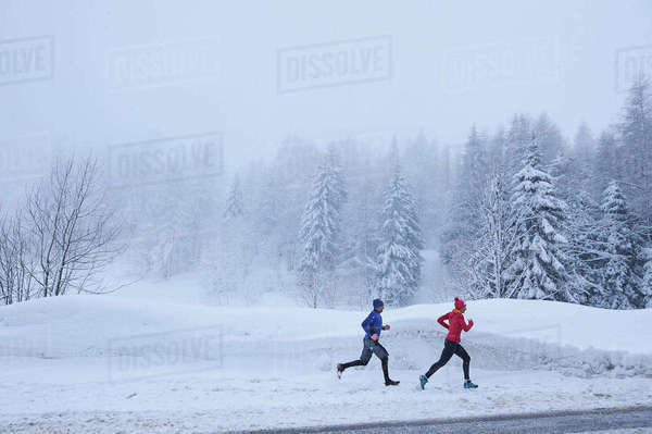 Distant view of female and male runners running in deep snow, Gstaad ...