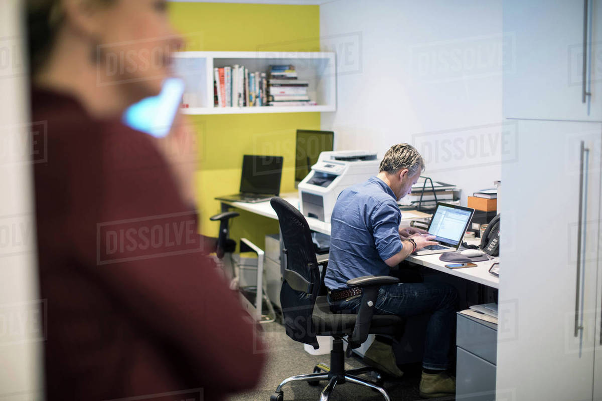 Man sitting at desk in office using laptop computer - Royalty-free ...