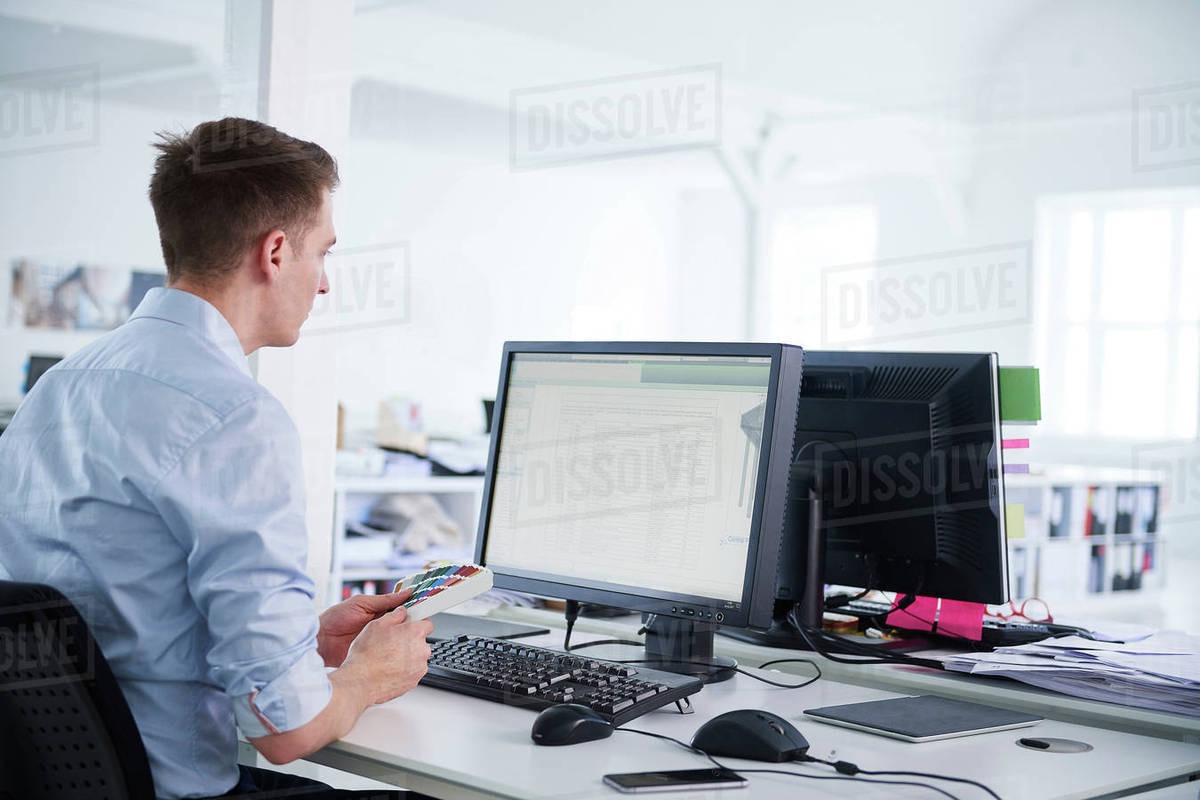 Man in office using computer - Stock Photo - Dissolve