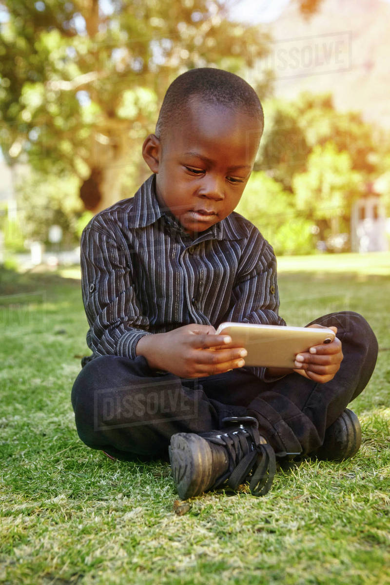 Boy playing game on cellular phone - Stock Photo - Dissolve