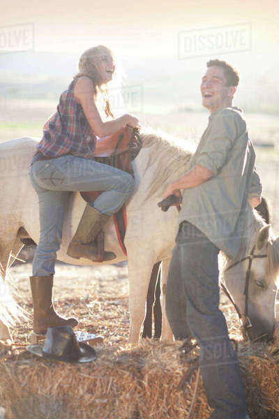 Young woman mounting horse with man laughing - Royalty-free Stock Photo ...