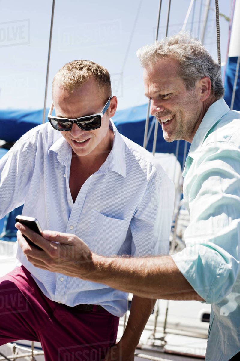 Two men on yacht with smartphone - Stock Photo - Dissolve