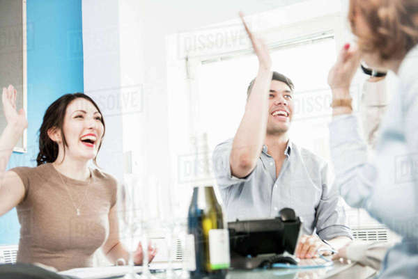 Colleagues giving high fives in office, champagne on table - Royalty ...