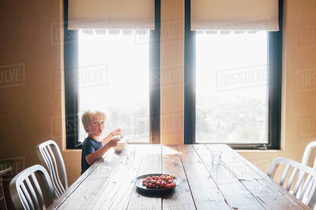 Boy sitting at dining table looking at camera, surprised, Fairfax ...