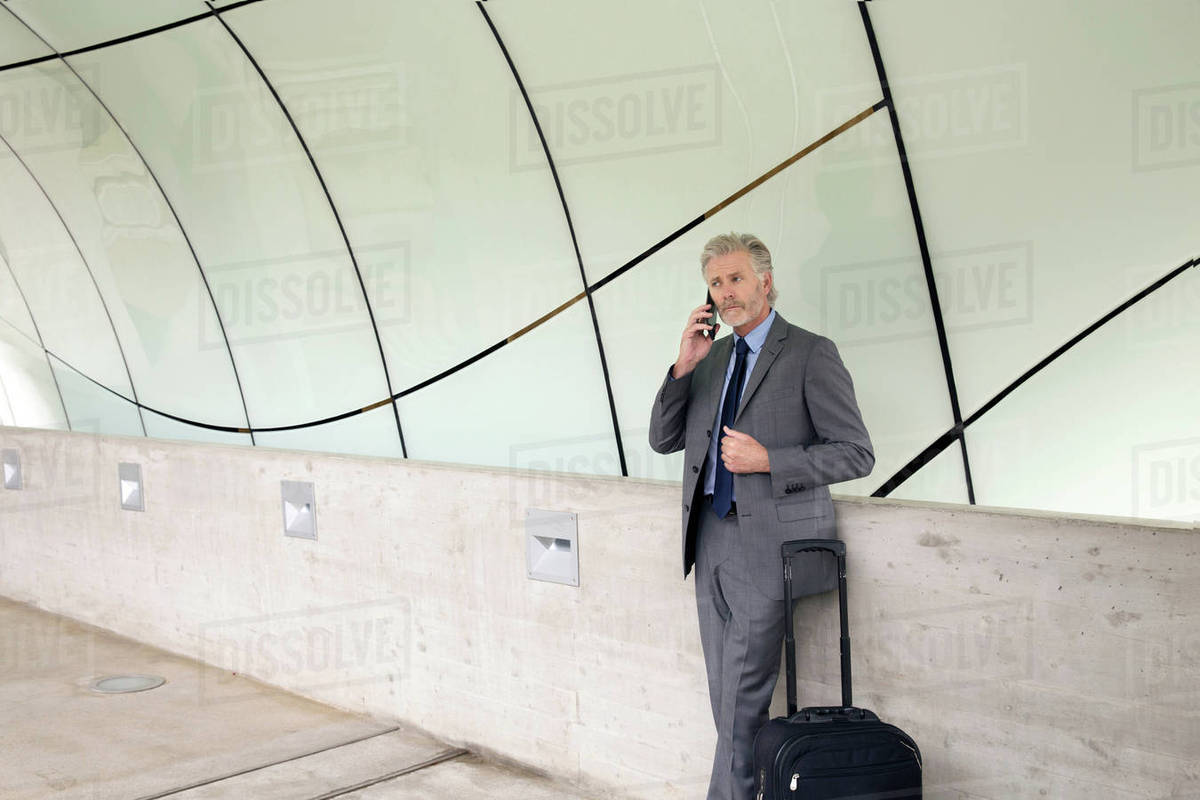 Businessman with suitcase making telephone call on smartphone - Royalty ...