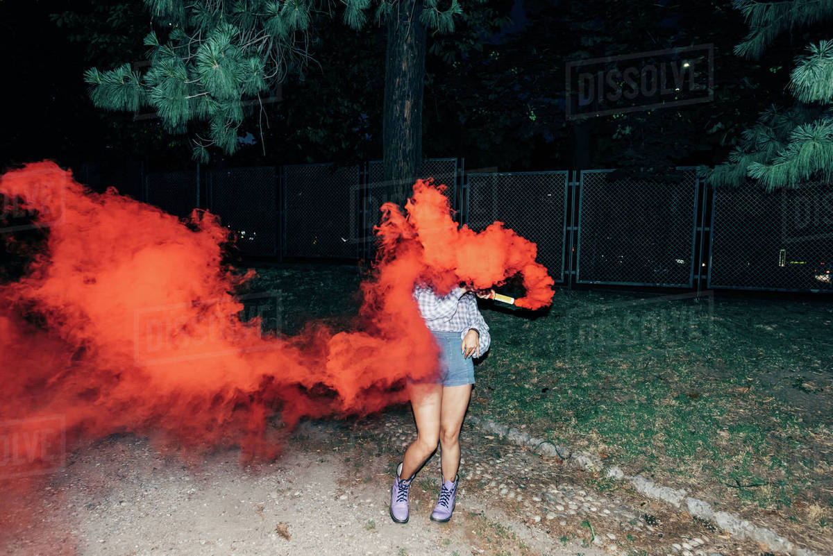 Woman holding flare in park at night - Stock Photo - Dissolve