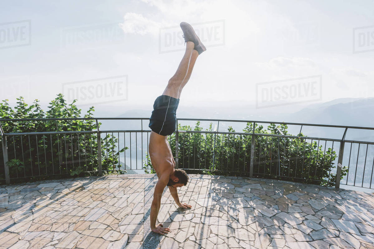 Young man doing handstand on viewing platform, Lake Como, Lombardy ...