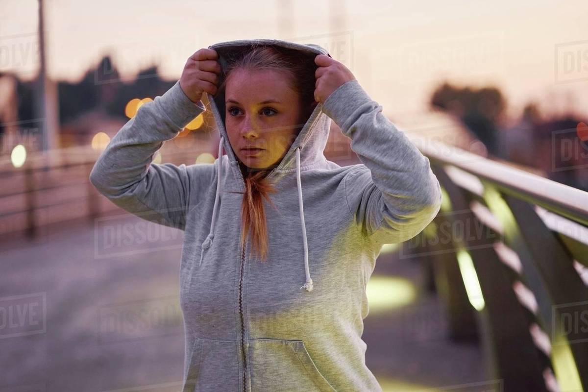 Curvaceous young woman training, getting hoody ready on footbridge at ...
