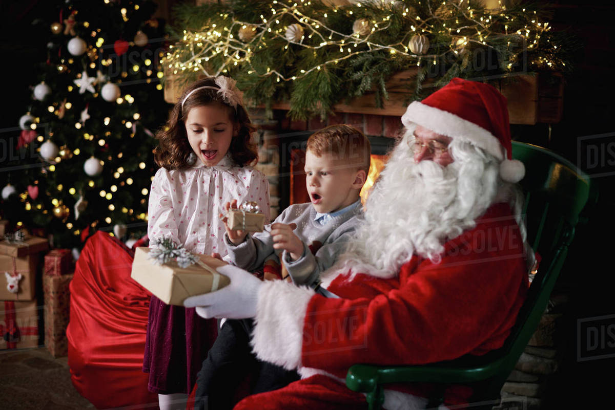 Young girl and boy visiting Santa, receiving gifts - Stock Photo - Dissolve