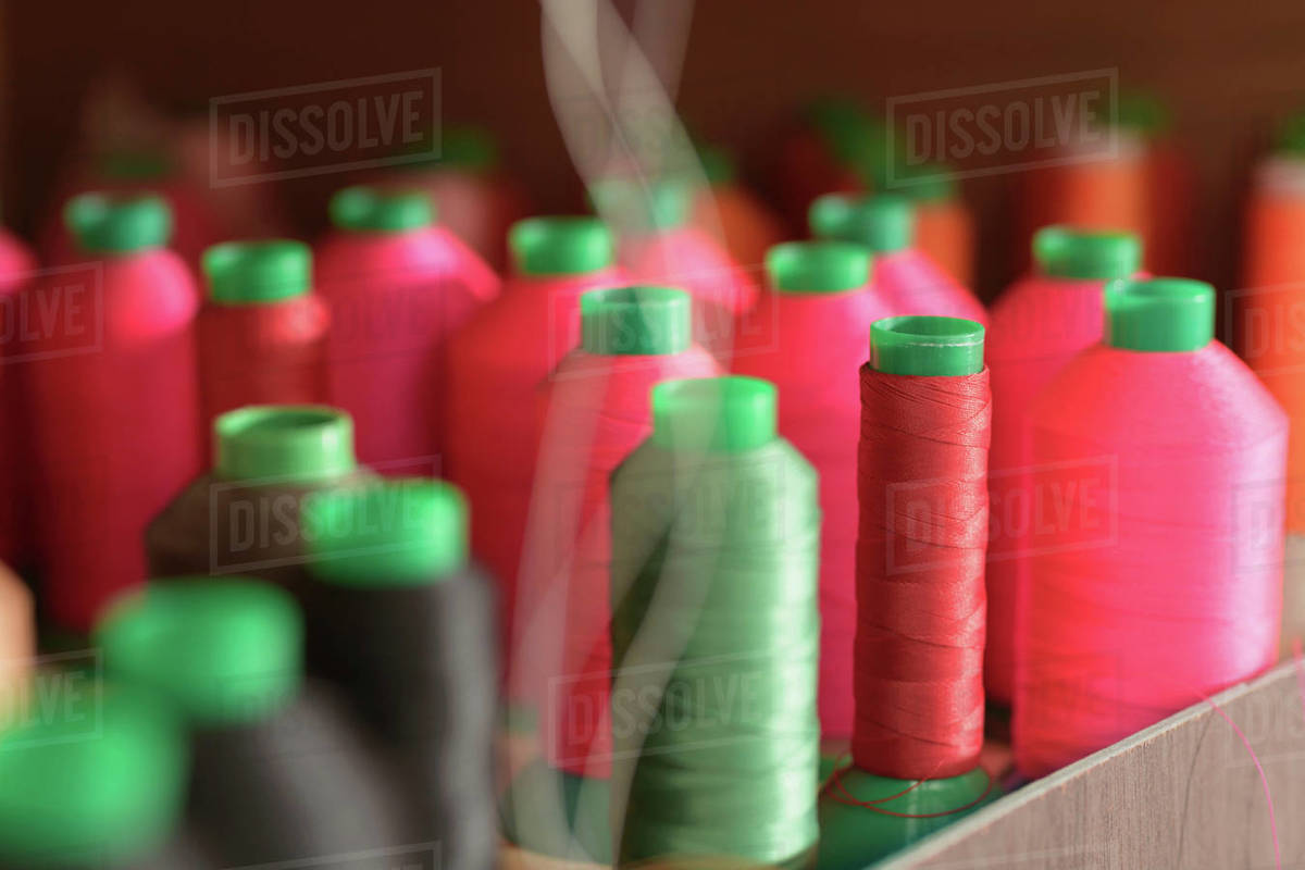 Red and green coloured threads in factory - Stock Photo - Dissolve