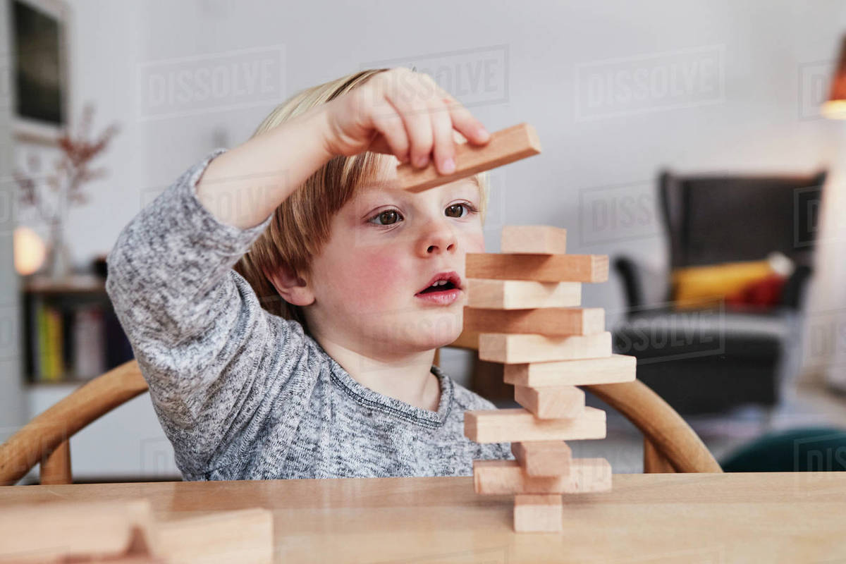 Portrait of young boy, building structure with wooden building blocks ...