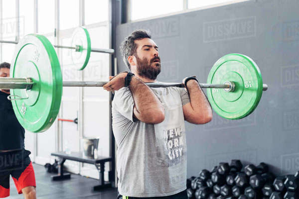 Man weightlifting with barbell in gym - Stock Photo - Dissolve