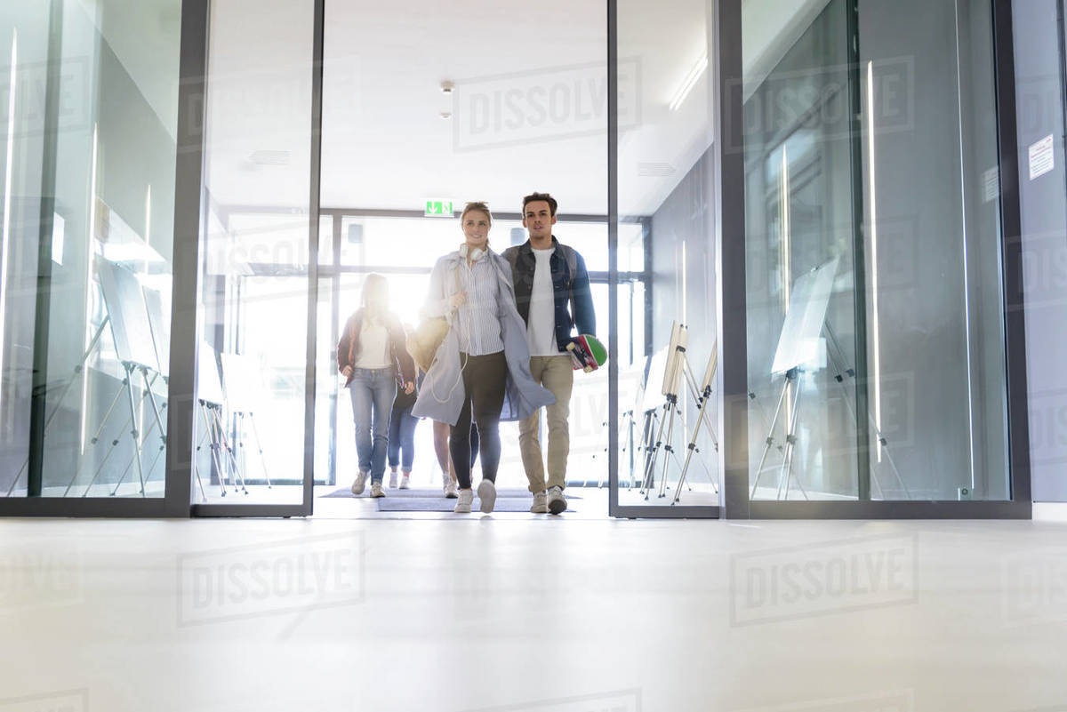 Students entering college building by glass doors - Stock Photo - Dissolve