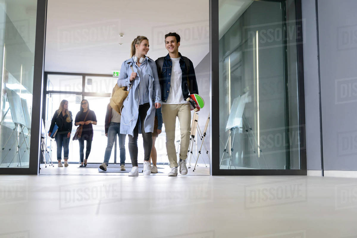 Students entering college building by glass doors - Stock Photo - Dissolve