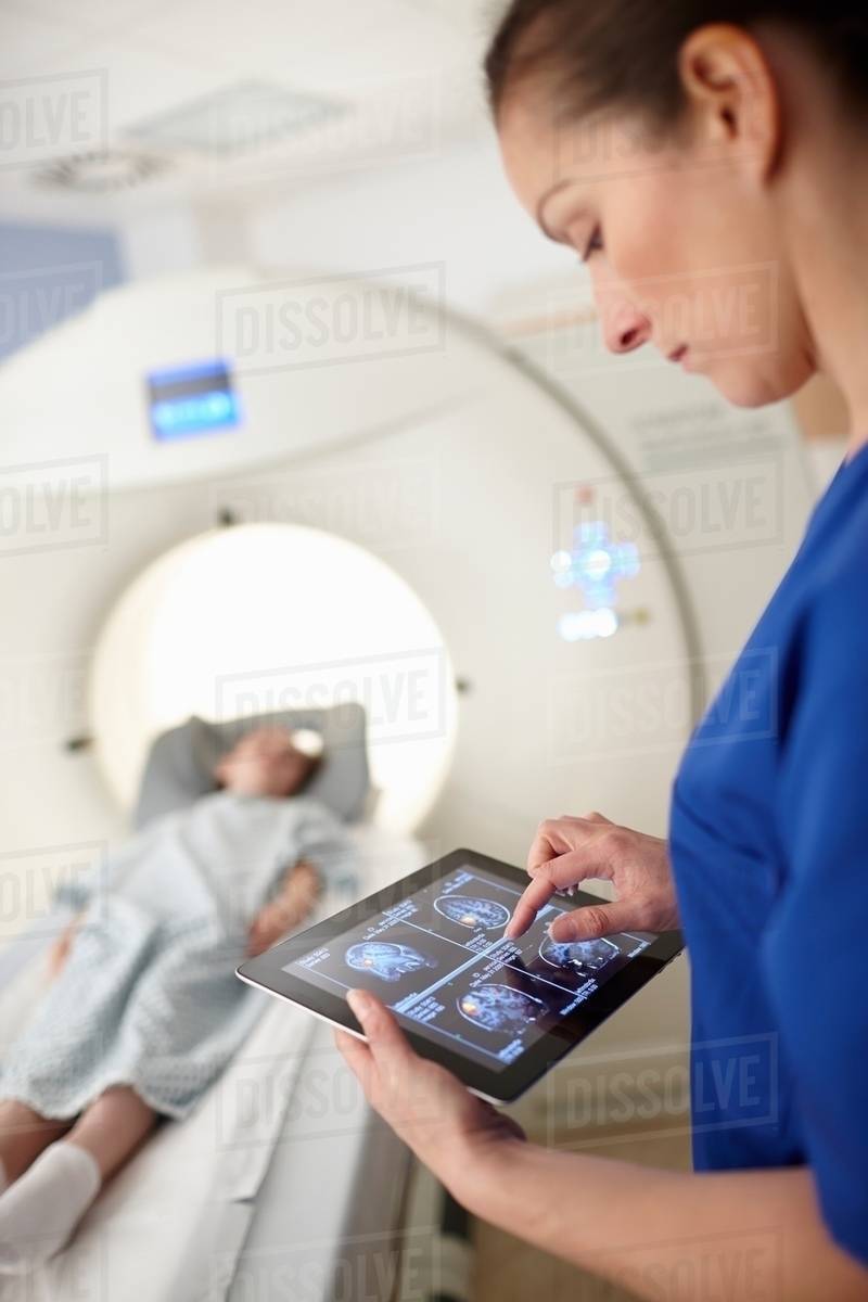 Radiographer looking at brain scan image on digital tablet - Stock ...