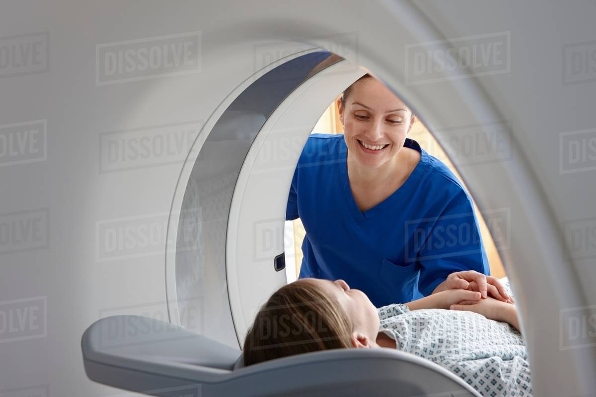 Radiographer smiling at girl inside CT scanner - Royalty-free Stock ...