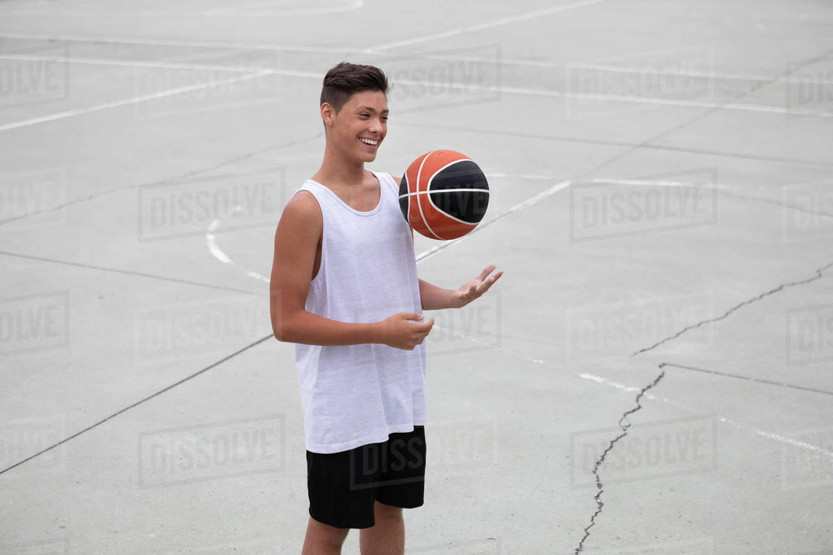 Male teenage basketball player on basketball court throwing and ...