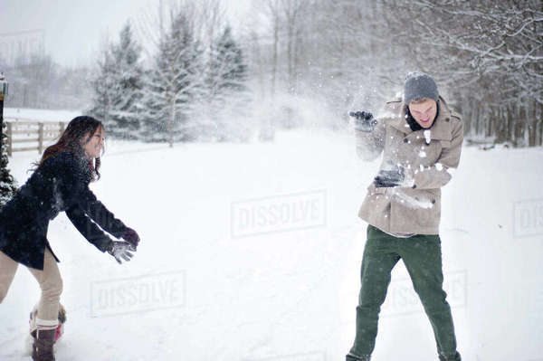 Young couple having snowball fight in snow covered forest, Ontario ...