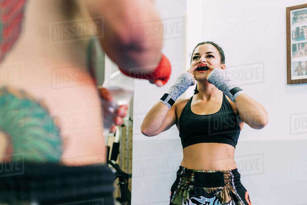 Female boxer putting on mouth guard - Stock Photo - Dissolve