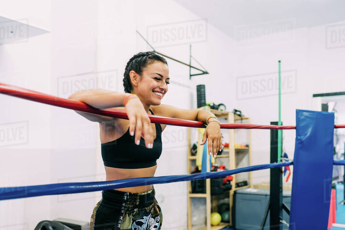 Laughing female boxer leaning over boxing ring ropes - Stock Photo ...