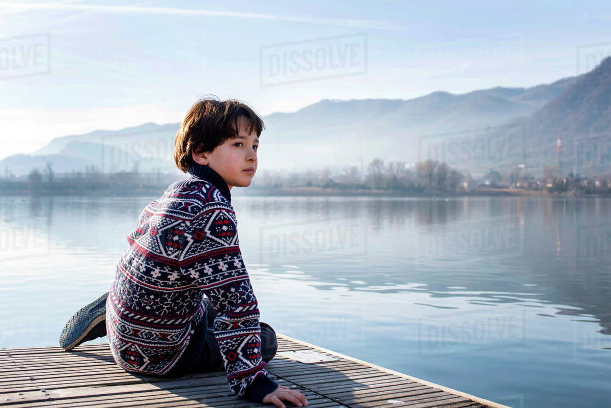 Boy looking back from lakeside pier, Lake Como, Lecco, Lombardy, Italy ...