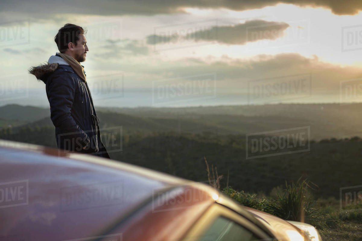 Man resting against car on roadside, enjoying view on hilltop - Royalty ...