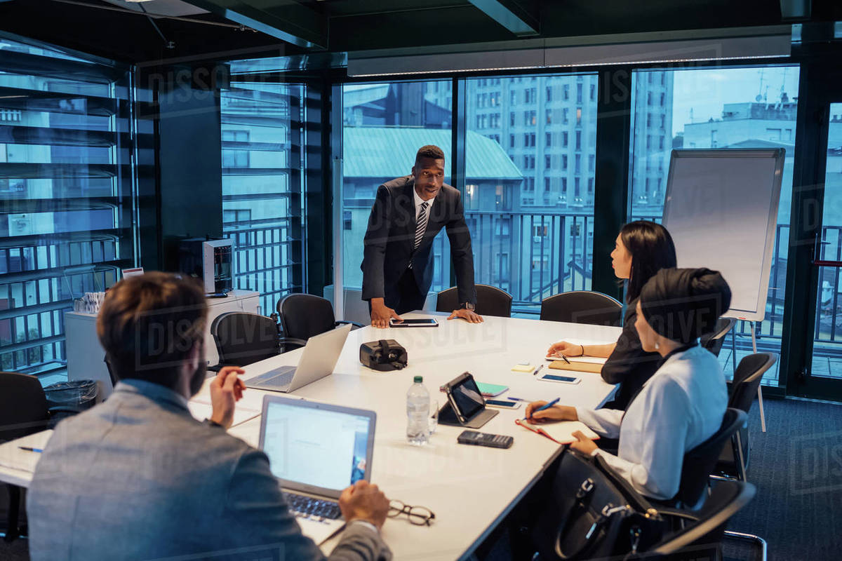 Businessman talking to team during conference table meeting - Royalty ...